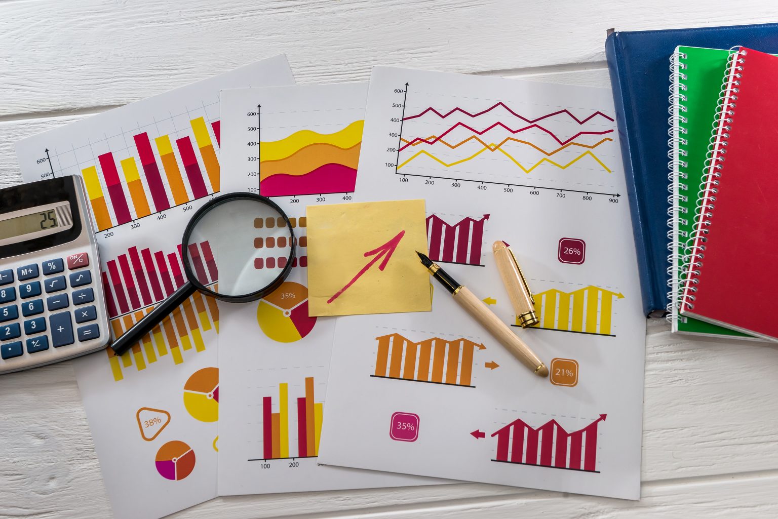 Top view of business graphs with magnifier, pen and calculator - GTC